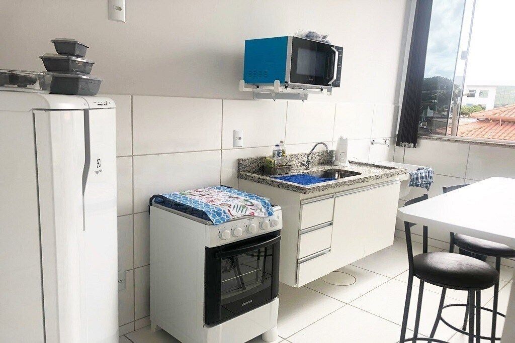Uma cozinha compacta com micro-ondas, forno e um balcão pequeno.