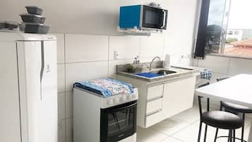 Uma cozinha compacta com micro-ondas, forno e um balcão pequeno.