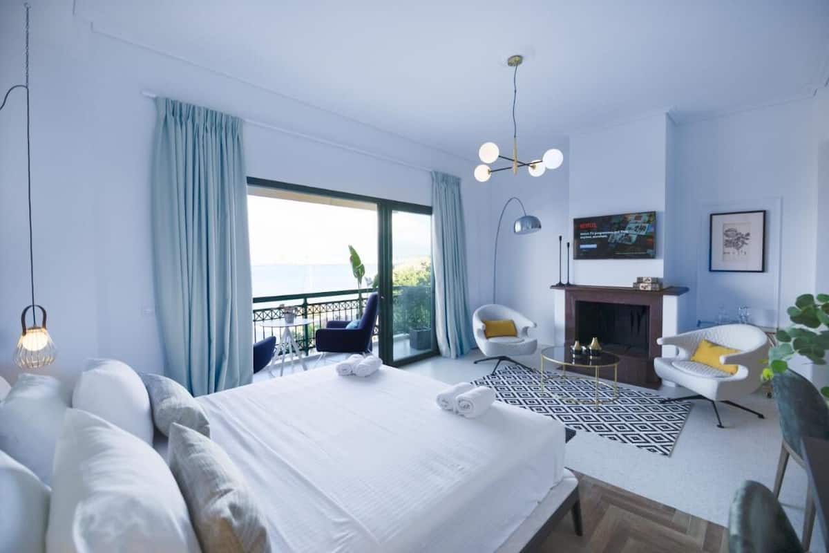 Quarto de hotel moderno com uma cama grande, varanda, lareira e vista para o exterior.