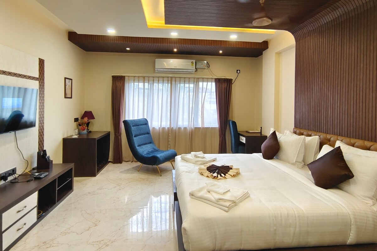 Quarto de hotel moderno com uma cama grande, uma TV de tela plana, uma escrivaninha e um ar condicionado.