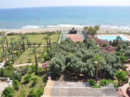 Um resort com vista para a praia, quadra de tênis e piscina.