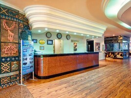Uma área de recepção com piso de madeira, balcão de atendimento e parede com desenhos decorativos.