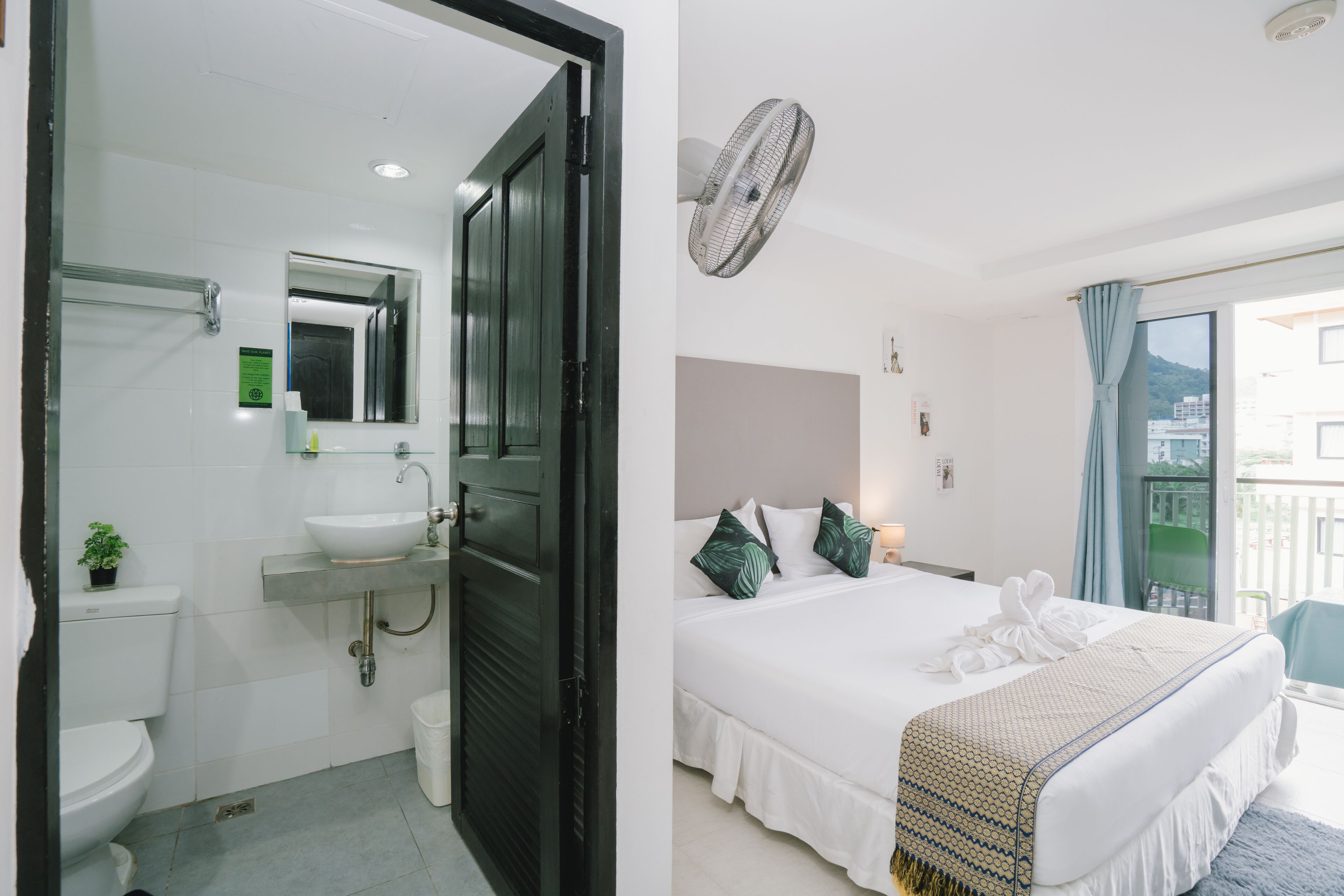 Quarto de hotel com cama, mesa de cabeceira e vista para o exterior.