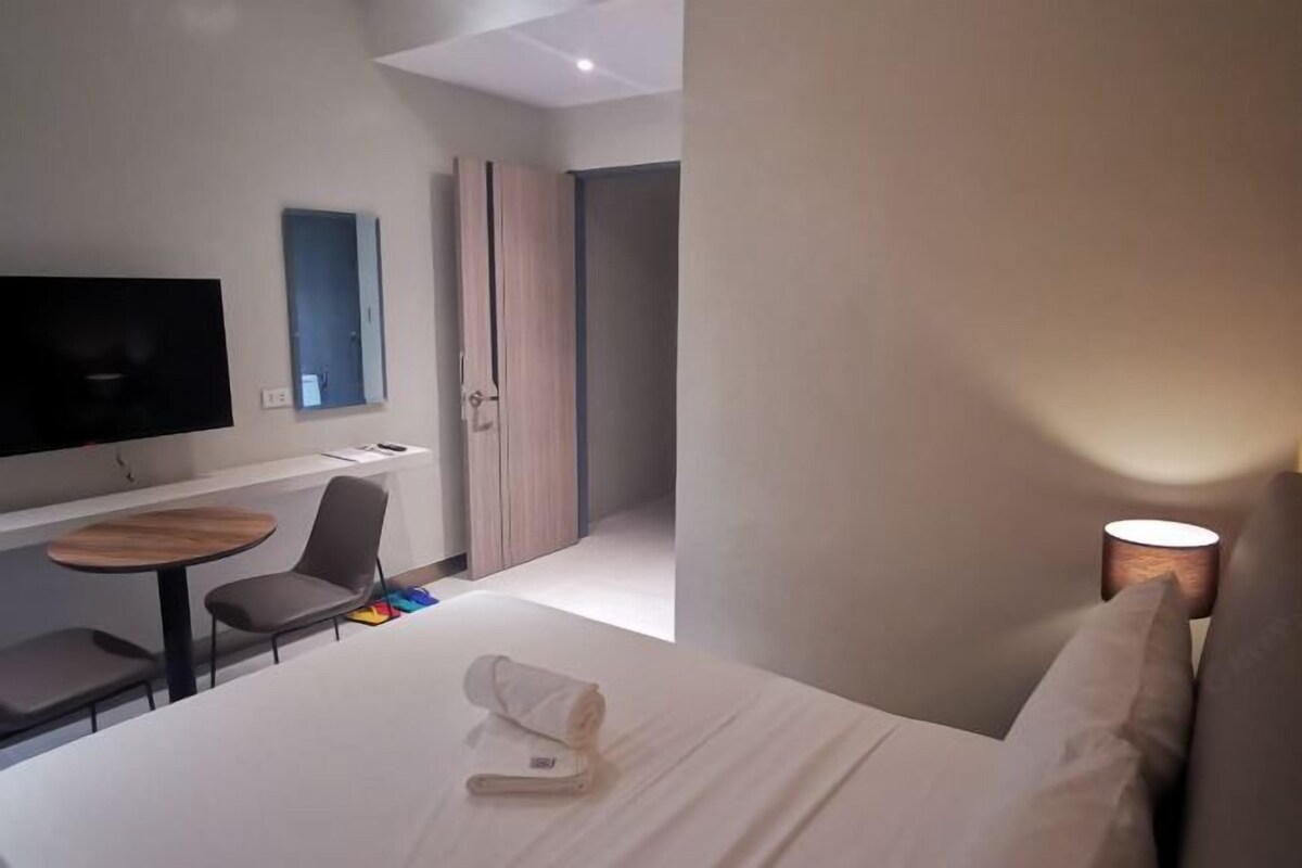 Quarto de hotel moderno com cama, televisão, escrivaninha e cadeira.