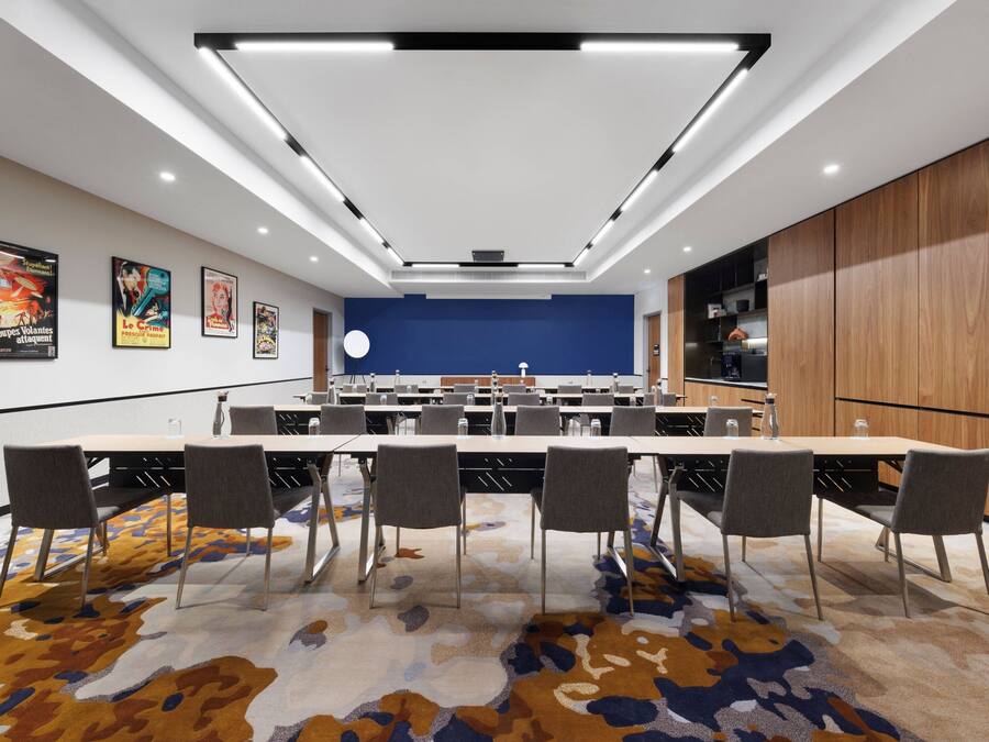 Uma sala de conferências com uma mesa comprida, cadeiras e uma parede azul de destaque.