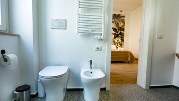 Uma casa de banho moderna com sanita, bidé e porta-toalhas.