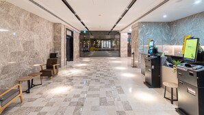 Um hall de hotel com balcão de check-in, área de estar e mesa de recepção.