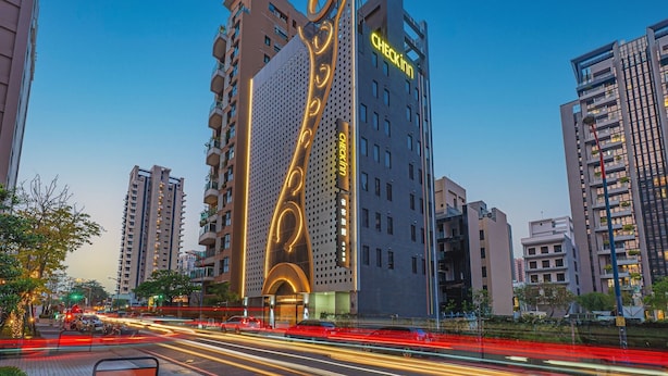 Um hotel moderno com uma entrada em arco marcante e um sinal grande com a palavra 'CHECKIN'.