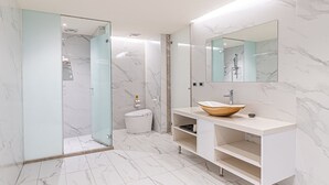 Uma casa de banho moderna com cabine de duche em vidro, sanita branca, chão em mosaico de mármore e espelho com lavatório em cerâmica de madeira.