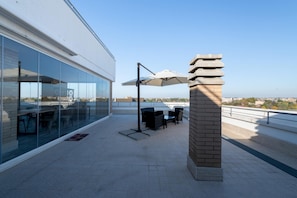 Terraço no terraço com parede de vidro, área de estar externa e coluna de pedra.