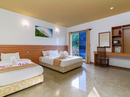 Quarto de hotel com duas camas, uma escrivaninha, uma cadeira, uma janela grande com vista para o verde e um quadro na parede.