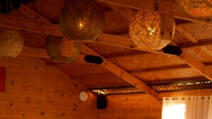 Aula de yoga em um espaço com piso e paredes de madeira, com uma janela grande e cortinas.