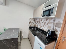 Uma cozinha compacta com micro-ondas, fogão e geladeira.