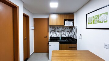Uma cozinha compacta com micro-ondas, fogão e lava-louças.