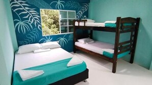 Quarto com beliche, janela com vista para área verde e parede com padrão de folhas.