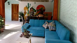 Uma sala de estar moderna com um sofá azul, uma porta de madeira e uma obra de arte abstrata colorida na parede.