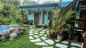 Um quintal com piscina, caminho de pedra e diversos vasos de plantas.