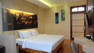 Quarto de hotel moderno com uma cama grande, uma escrivaninha e uma televisão.