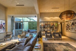 Uma sala de estar ampla, com sofá, cadeiras, mesa de centro e estante de livros.