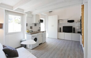 Um apartamento compacto e moderno, com cozinha compacta, máquina de lavar, área de refeições e televisão.