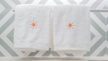 Duas toalhas brancas com desenhos de sol em laranja penduradas em um suporte.