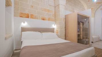 Quarto com parede de tijolos, guarda-roupa de madeira e cama com roupa de cama branca.