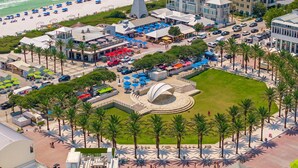 Um hotel à beira-mar com vista para a praia, diversas opções de restaurantes e uma praça central com palmeiras.