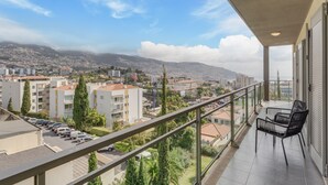 Varanda com vista para uma paisagem urbana, incluindo edifícios e uma cordilheira.