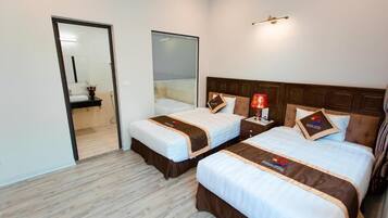 Quarto de hotel com duas camas, uma mesa de cabeceira, um espelho e uma porta que dá para o banheiro.