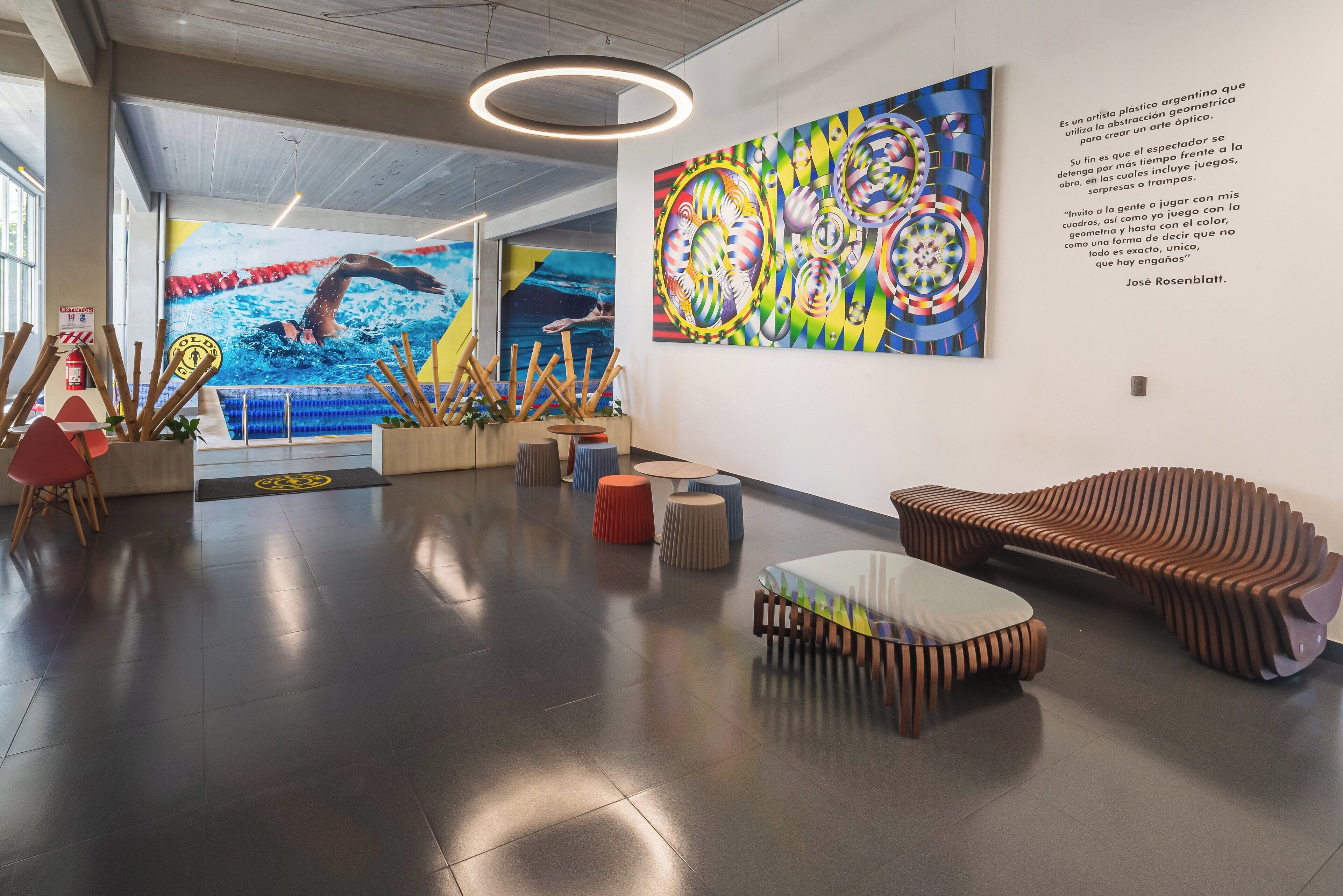Um espaço interno com piscina, obras de arte coloridas e assentos modernos.