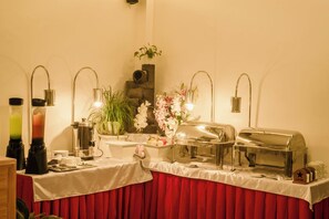 Uma mesa de buffet com diversos tipos de comida, um espaço para café e um arranjo decorativo.
