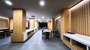 Um restaurante moderno com um balcão extenso, várias mesas e cabines.