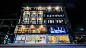 Um hotel com vários andares, varandas e uma entrada bem iluminada.