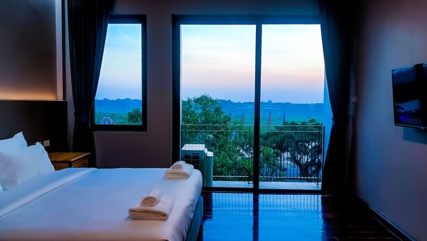 Quarto de hotel com uma cama grande, uma TV e uma varanda com vista para a paisagem.