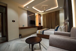 Quarto de hotel moderno com cama, sofá e uma pequena mesa.