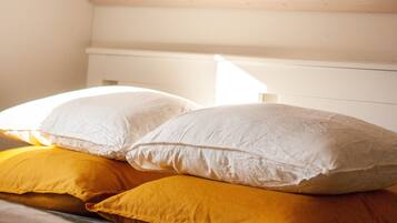 Cama com almofadas brancas e mostarda.