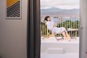 Uma pessoa relaxando em uma cadeira de varanda com vista para montanhas e um corpo de água.