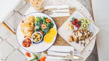 Uma mesa com pratos de comida, utensílios e um copo de bebida gelada.