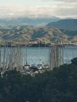 Uma marina com barcos atracados, rodeada por montanhas e árvores.