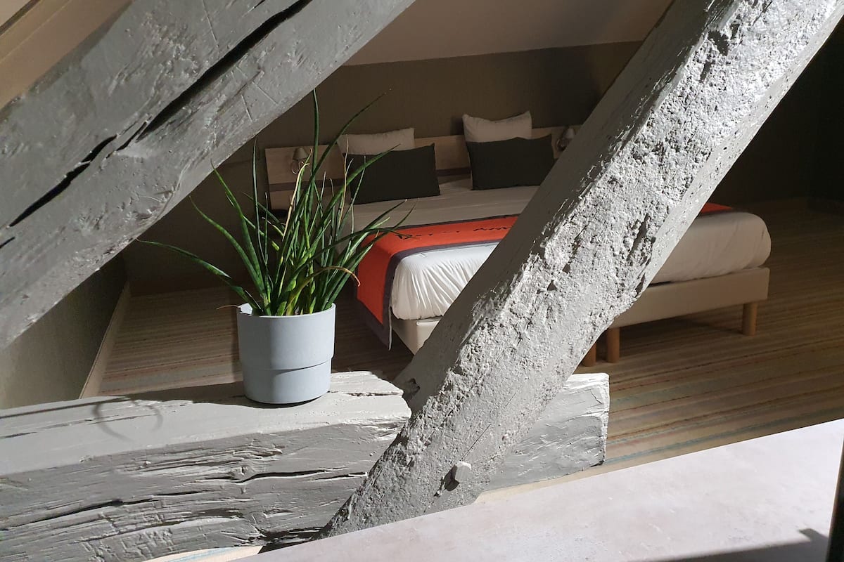 Quarto com cama, almofadas e uma planta em vaso.
