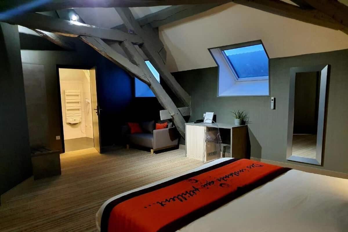 Quarto moderno com uma cama grande, uma escrivaninha, uma cadeira e um claraboia.
