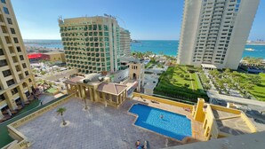 Um edifício alto com área de piscina, incluindo uma piscina e um solário.