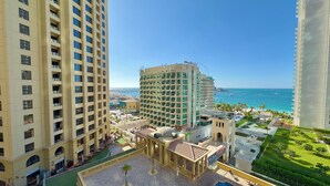 Um hotel alto com várias varandas, um pátio central com assentos e vista para o mar.