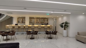 Um lobby moderno com área de bar, assentos e escadaria.
