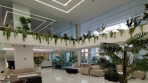 Um hall amplo com pé direito alto, móveis modernos e plantas em vasos.