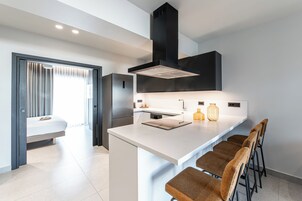Uma cozinha moderna com ilha central, banquetas e fogão embutido.