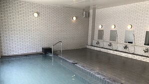 Piscina com chão e paredes azulejadas, cercada por espelhos e luzes.