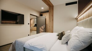 Quarto de hotel moderno com uma cama grande, televisão de tela plana na parede e um painel de parede em madeira.