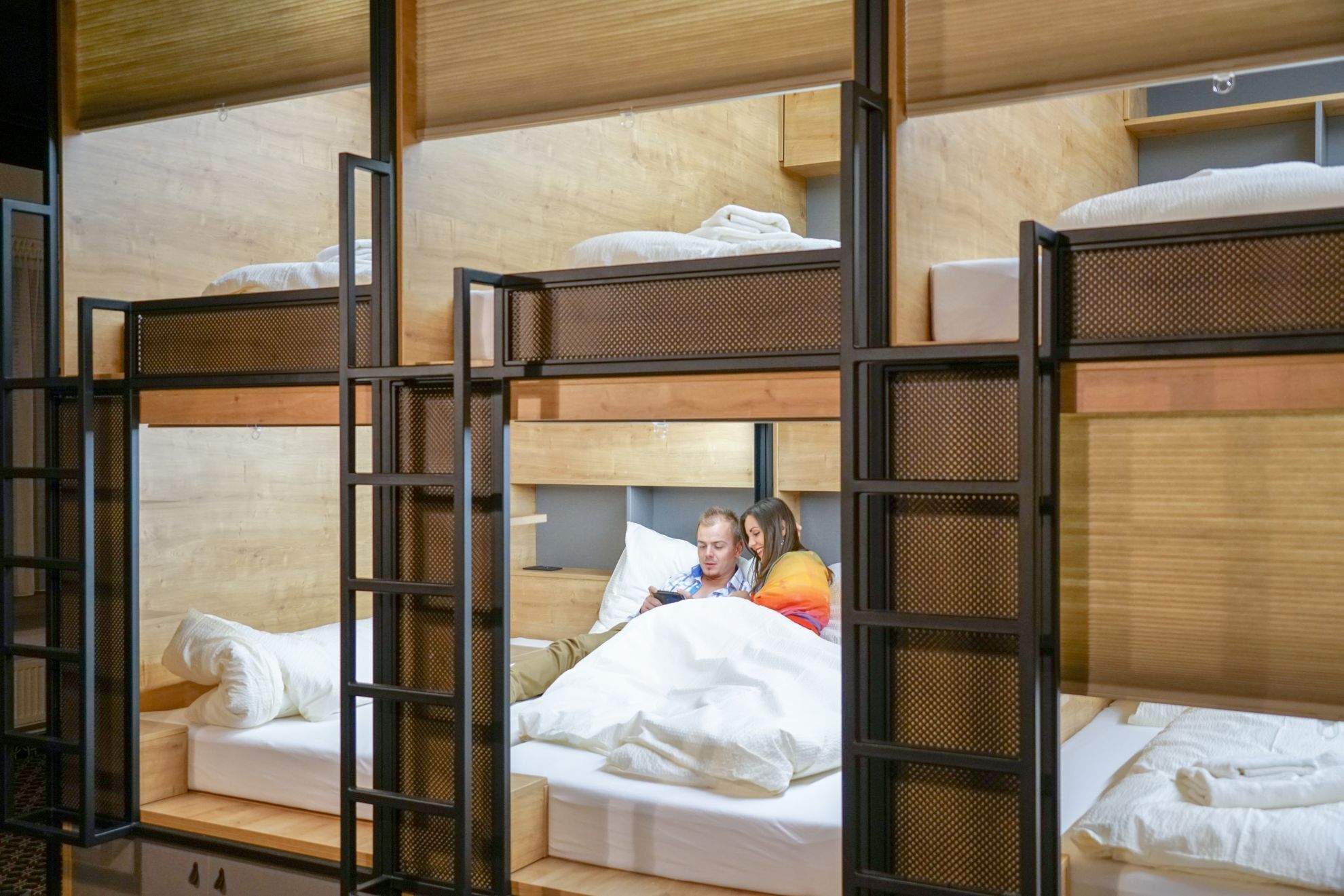 Quarto com beliches de madeira e grades de metal.