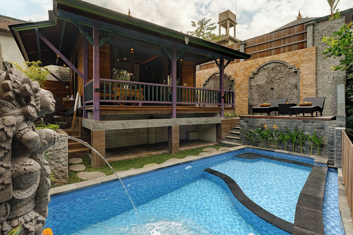 Uma piscina com parede de pedra e deck de madeira.